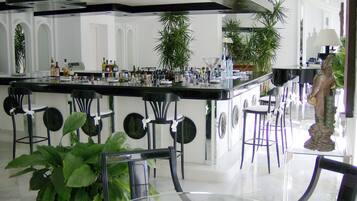 Cozinha moderna com balcão central, diversas cadeiras e plantas em vasos.