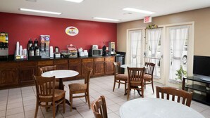 Espaço para café da manhã com parede vermelha, estação de café e televisão.
