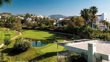 Um campo de golfe com lago, rodeado por vegetação exuberante e palmeiras.
