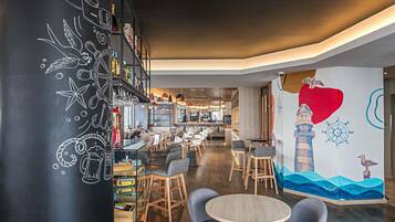 Um interior moderno com área de bar, assentos e um mural.