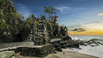 Um templo de pedra com uma escadaria que leva a uma plataforma de observação com vista para o oceano.