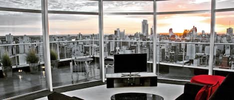 Uma sala de estar moderna com uma TV grande, uma mesa de centro redonda e um sofá.