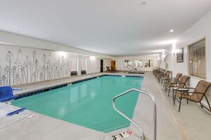 Piscina com borda azulejada, uma cadeira azul e fileira de cadeiras marrons à beira da piscina.