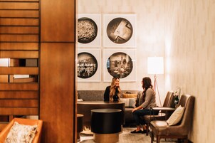 Um lobby moderno com balcão de atendimento, área de estar e fotografias emolduradas na parede.