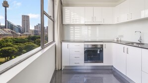 Cozinha moderna com armários brancos, forno embutido e uma janela ampla com vista para a cidade.