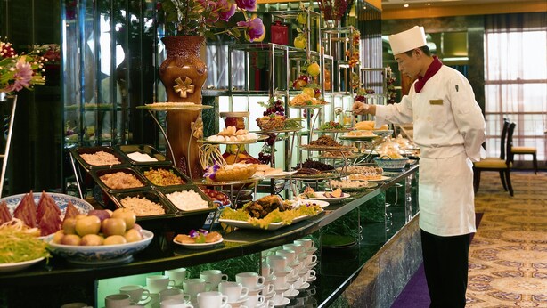 Disposição de buffet com diversos alimentos e um chef a servir.