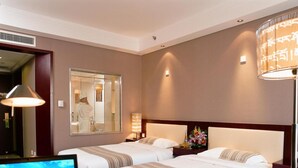 Quarto de hotel com duas camas, uma escrivaninha com um laptop, uma chávena de café e uma revista.