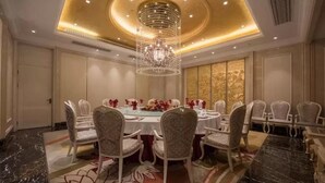 Uma sala de jantar formal com uma mesa redonda, cadeiras estofadas brancas e um lustre grande.