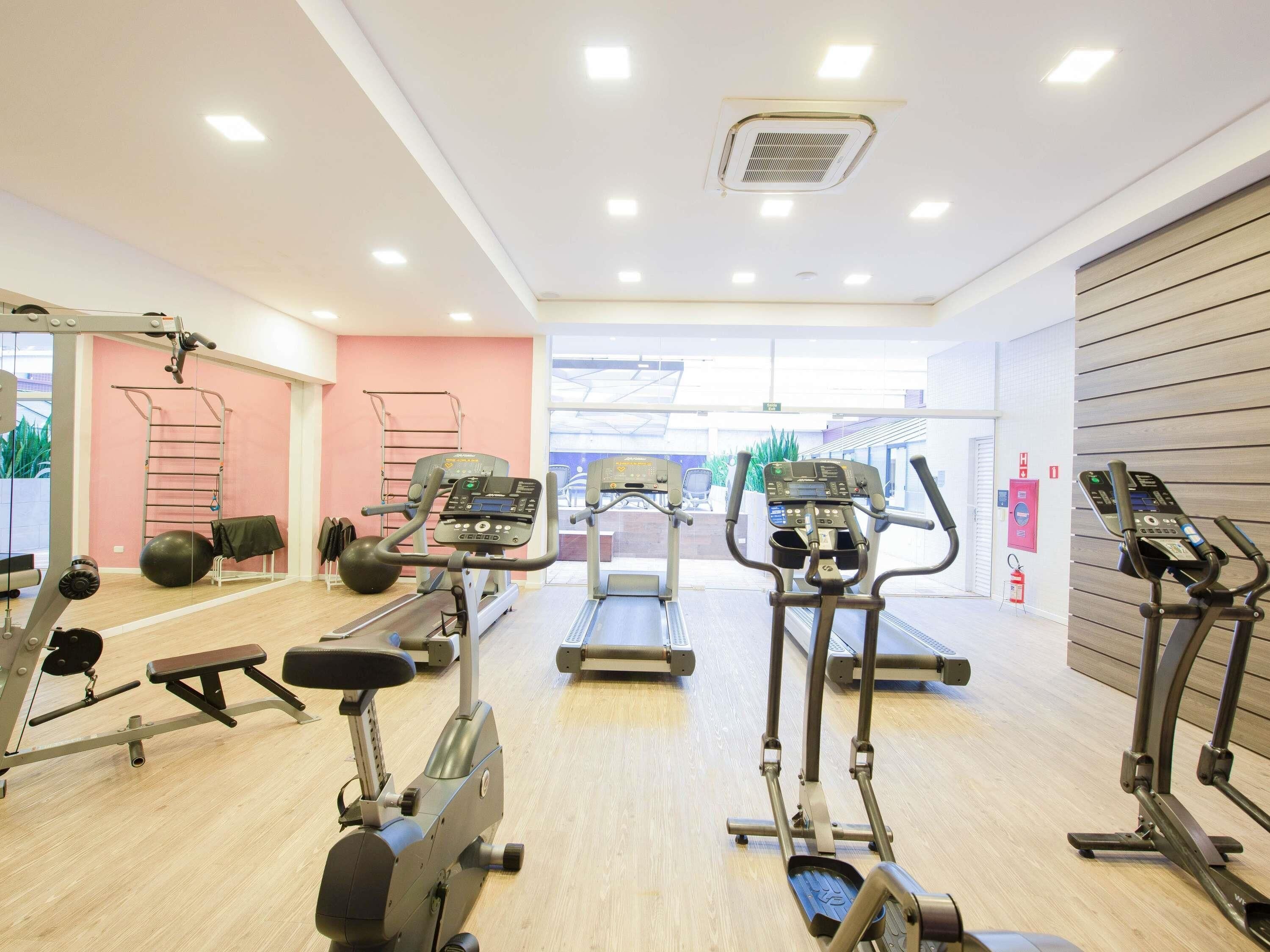Uma academia com esteiras, elípticos e equipamentos de musculação.