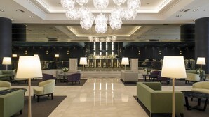 Um hall amplo com bar central, várias áreas de estar e um lustre.