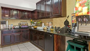 Uma cozinha com armários de madeira escura, máquina de café, torradeira e geladeira.