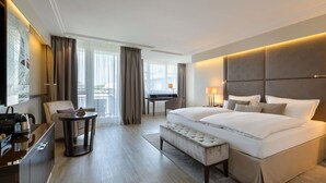 Quarto de hotel moderno com uma cama grande, uma escrivaninha, uma cadeira e vista para o exterior.