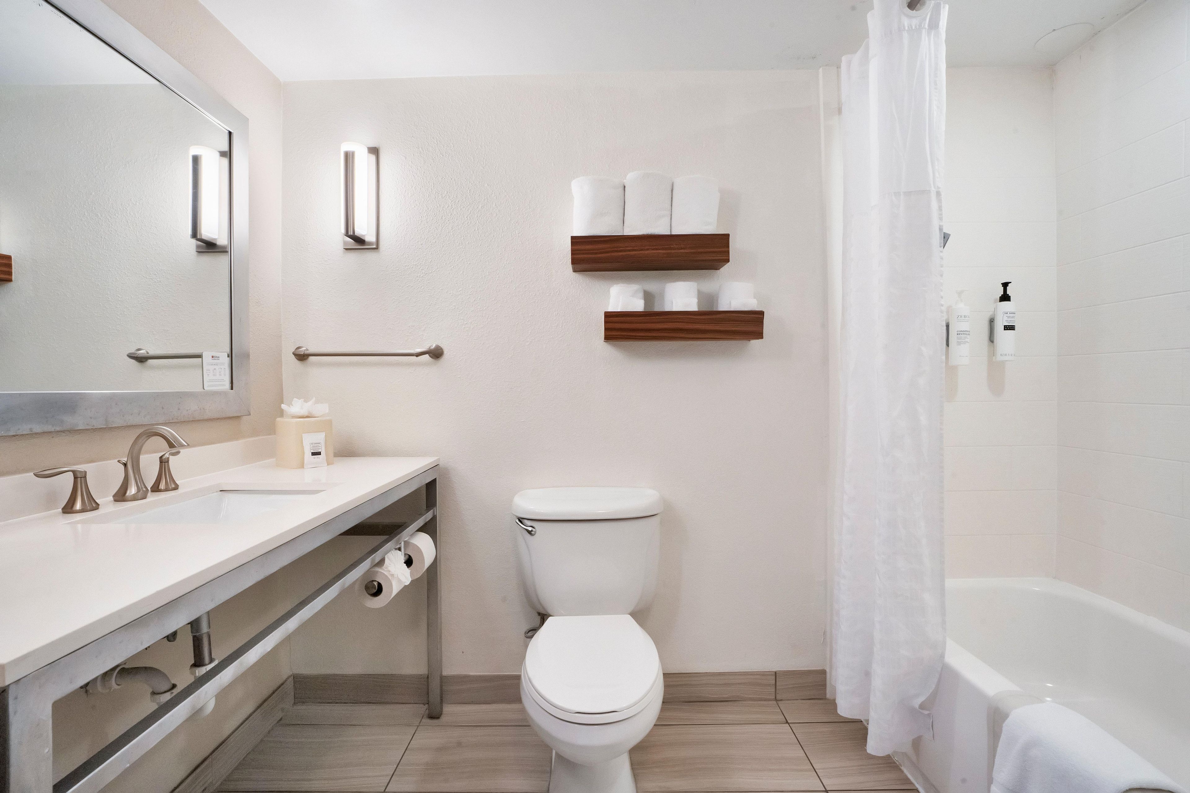 Uma casa de banho moderna com sanita branca, lavatório com espelho e cabine de duche.