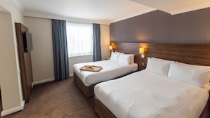 Quarto de hotel com duas camas, televisão, janela com cortinas e bandeja com itens de café da manhã.