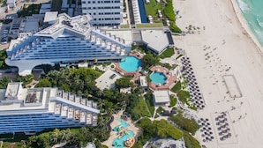 Um resort com várias piscinas, uma praia e uma grande estrutura de hotel.