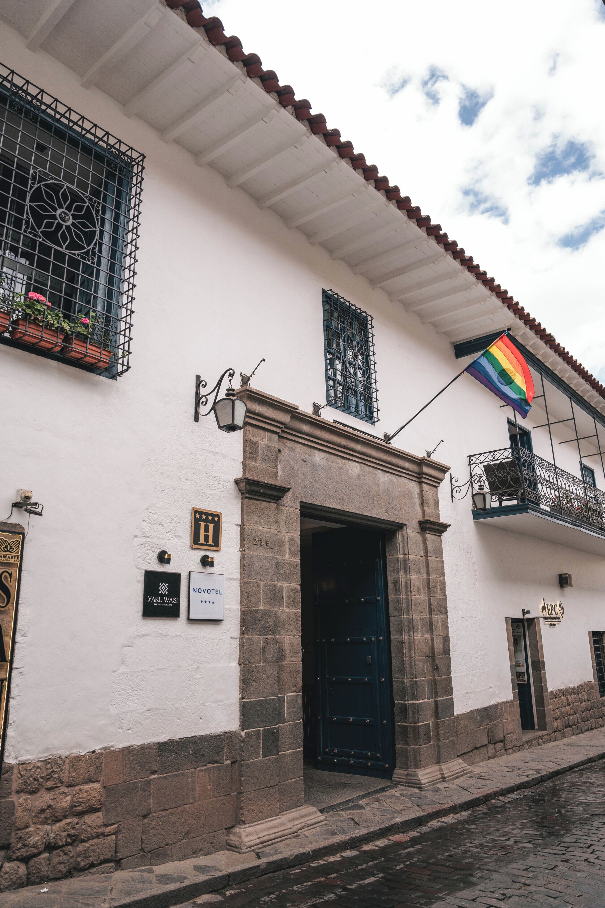 Um edifício com porta preta, uma placa com a inscrição 'NOVOTEL' e uma bandeira.