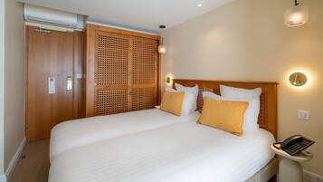 Quarto de hotel com uma cama grande, guarda-roupa de madeira e telefone ao lado da cama.