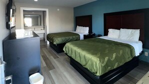 Quarto de hotel com duas camas, uma escrivaninha, uma televisão e uma lixeira.