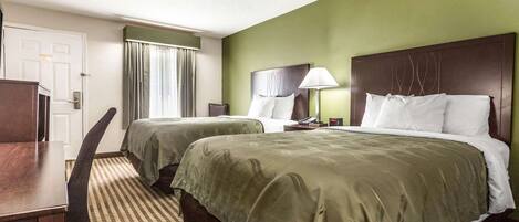 Quarto de hotel com duas camas, uma escrivaninha e uma cadeira.