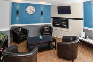 Um hall de entrada com parede azul decorativa, um relógio, lareira e assentos de couro.