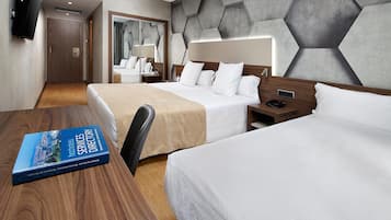 Quarto de hotel com duas camas, uma escrivaninha de madeira, um livro intitulado 'Hotel Services Directory' e um design moderno de parede geométrica.
