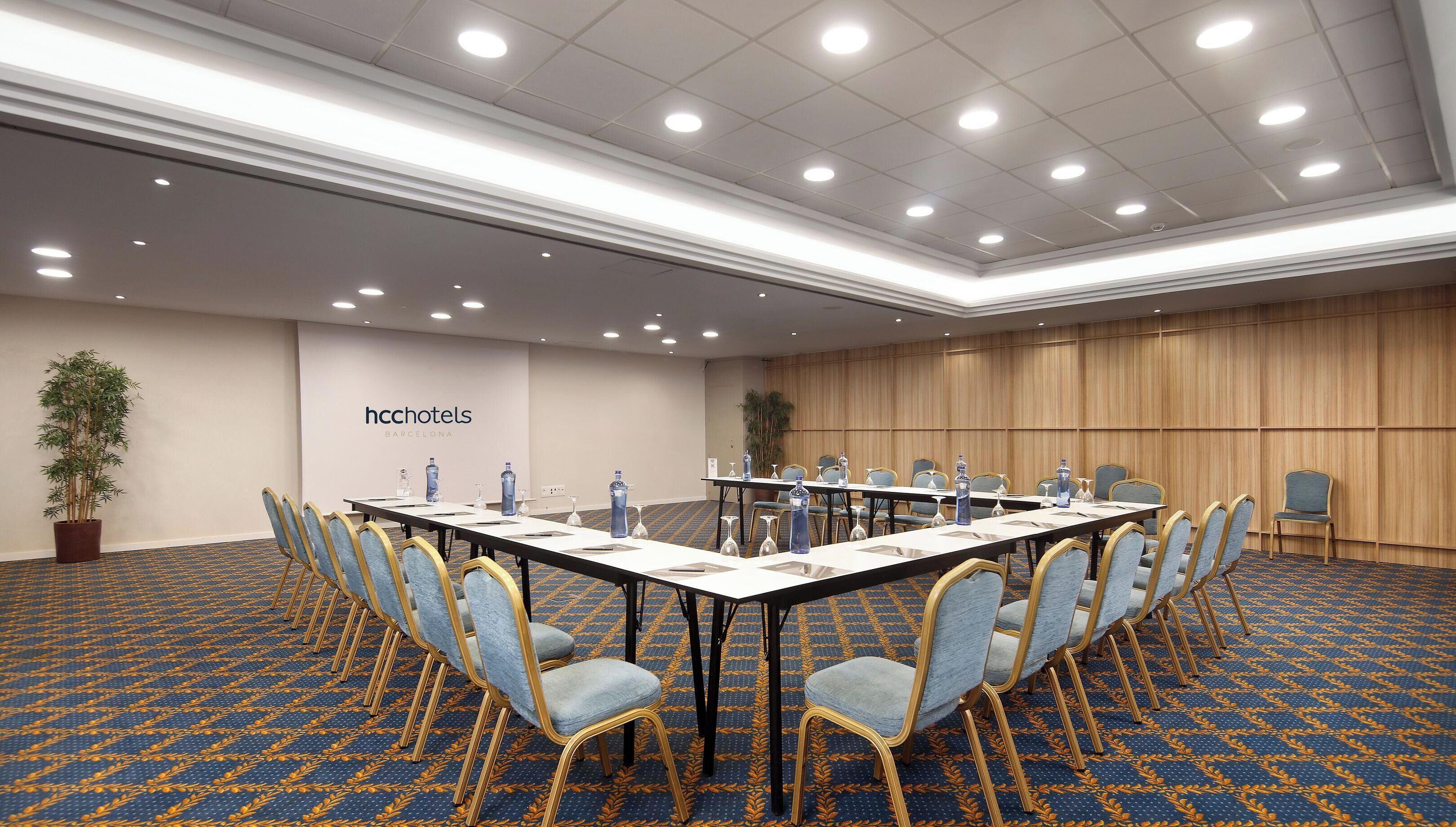 Sala de conferências com uma mesa comprida, cadeiras e um vaso de planta.