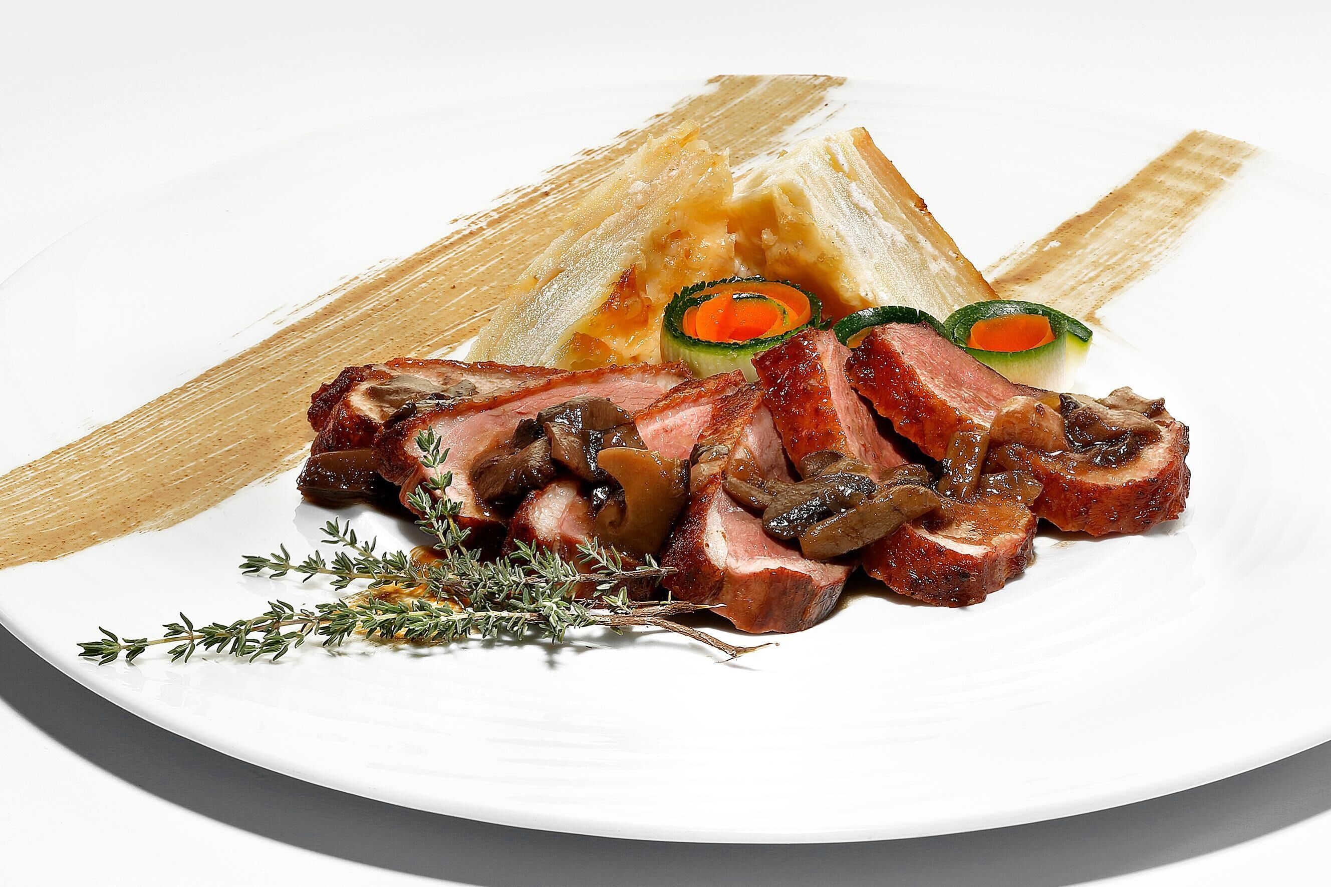 Um prato com carne fatiada, legumes e pão.
