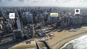 Vista aérea de uma cidade costeira com edifícios altos, uma praia e um píer.