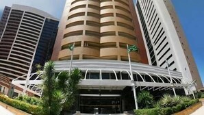 Um edifício alto e moderno, com entrada central e uma marquise curva.