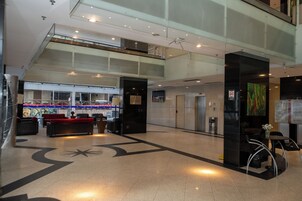 Um hall espaçoso com balcão de recepção, área de estar e uma grande janela de vidro com vista para a rua.