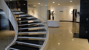 Escadaria em espiral com corrimão branco em uma área de lobby moderna.