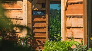 Uma cabana de madeira com telhado inclinado, uma porta com um letreiro e uma janela.