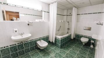 Uma casa de banho com lavatório, bidé, sanita e zona de duche.