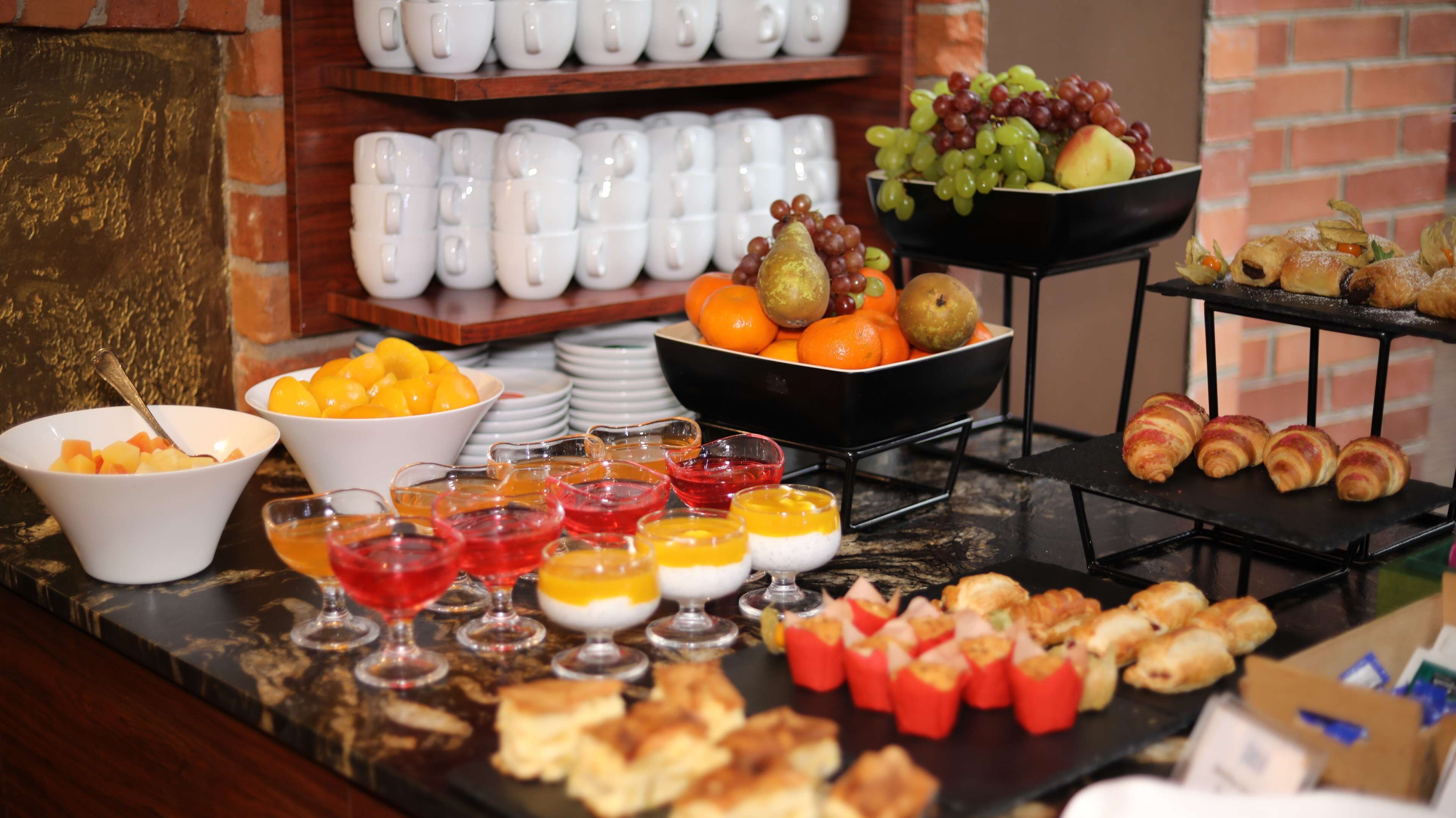 Buffet com diversas opções de comida, incluindo frutas, doces e sobremesas.