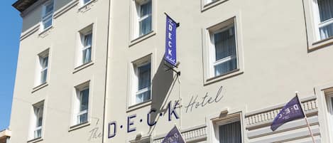 Um edifício com várias janelas e uma placa com a inscrição "The DECK Hotel".