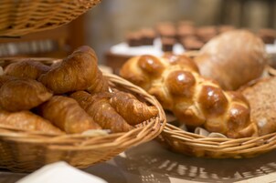 Uma cesta com diversos produtos de panificação, incluindo croissants e pão.