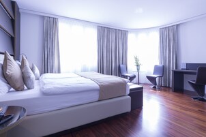 Quarto de hotel moderno com uma cama grande, uma escrivaninha e duas cadeiras.