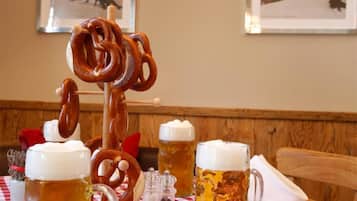 Uma mesa posta com canecas de cerveja, pretzels e um guardanapo branco sobre um tecido quadriculado.