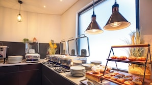Um buffet de café da manhã com diversas opções de comida e uma máquina de café.
