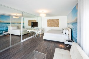 Quarto de hotel moderno com uma cama grande, uma escrivaninha e uma televisão.