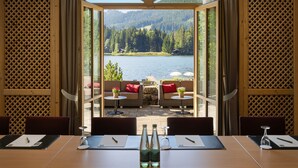 Quarto com vista para um lago e montanhas, mobiliado com uma mesa, cadeiras e um sofá.