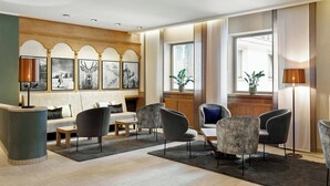 Um lobby moderno com um sofá, poltronas, uma mesa de centro e obras de arte emolduradas na parede.