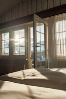 Quarto com uma cama grande, janela com vista para montanhas e porta que dá para uma varanda.