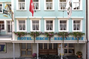Um hotel com uma placa indicando "HOTEL HECHT RESTAURANT" e uma bandeira vermelha.