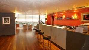 Uma área de bar com balcão, banquetas e uma parede de garrafas de bebidas.