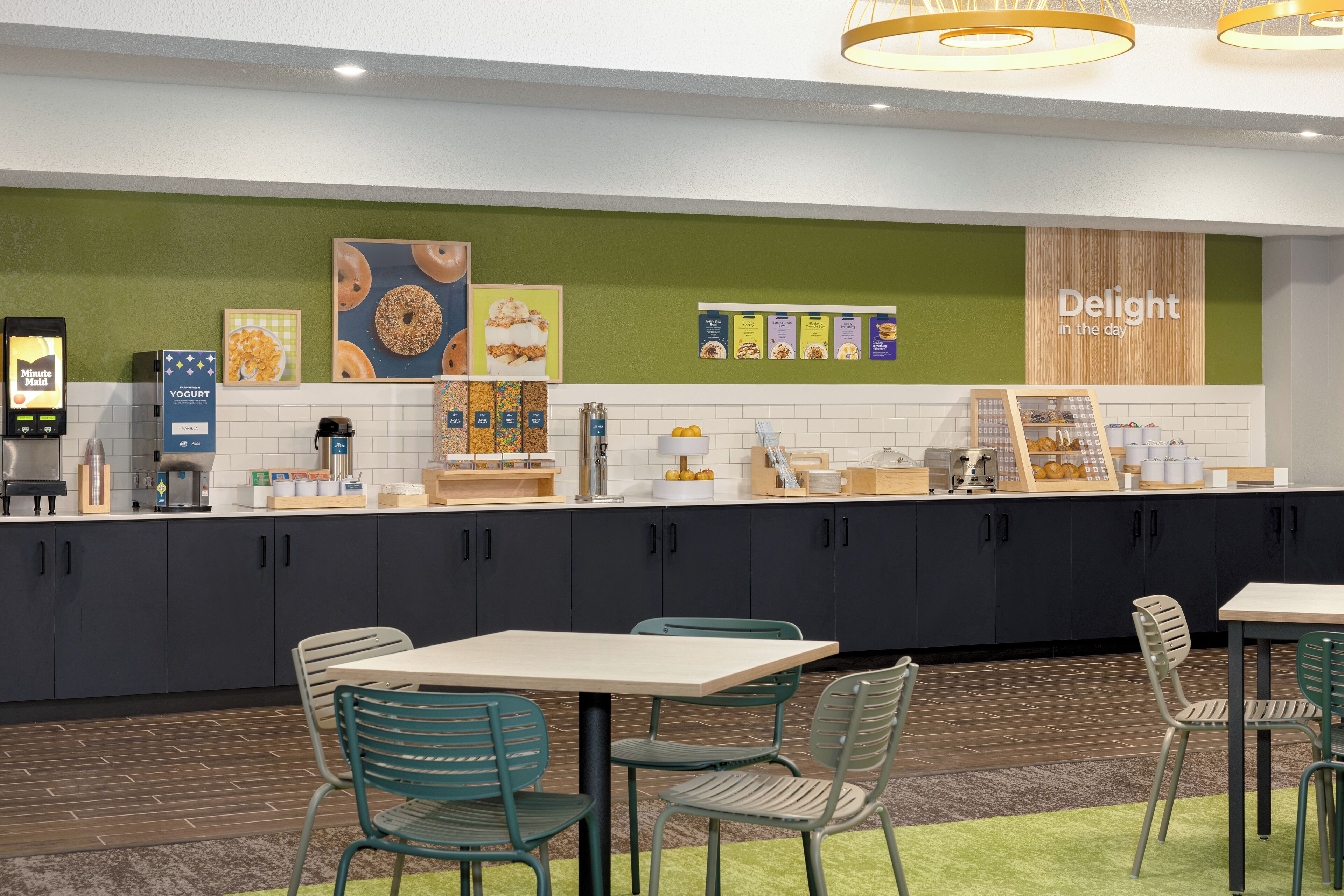 Um café moderno com parede verde, um quadro de menu e um balcão com diversos alimentos.