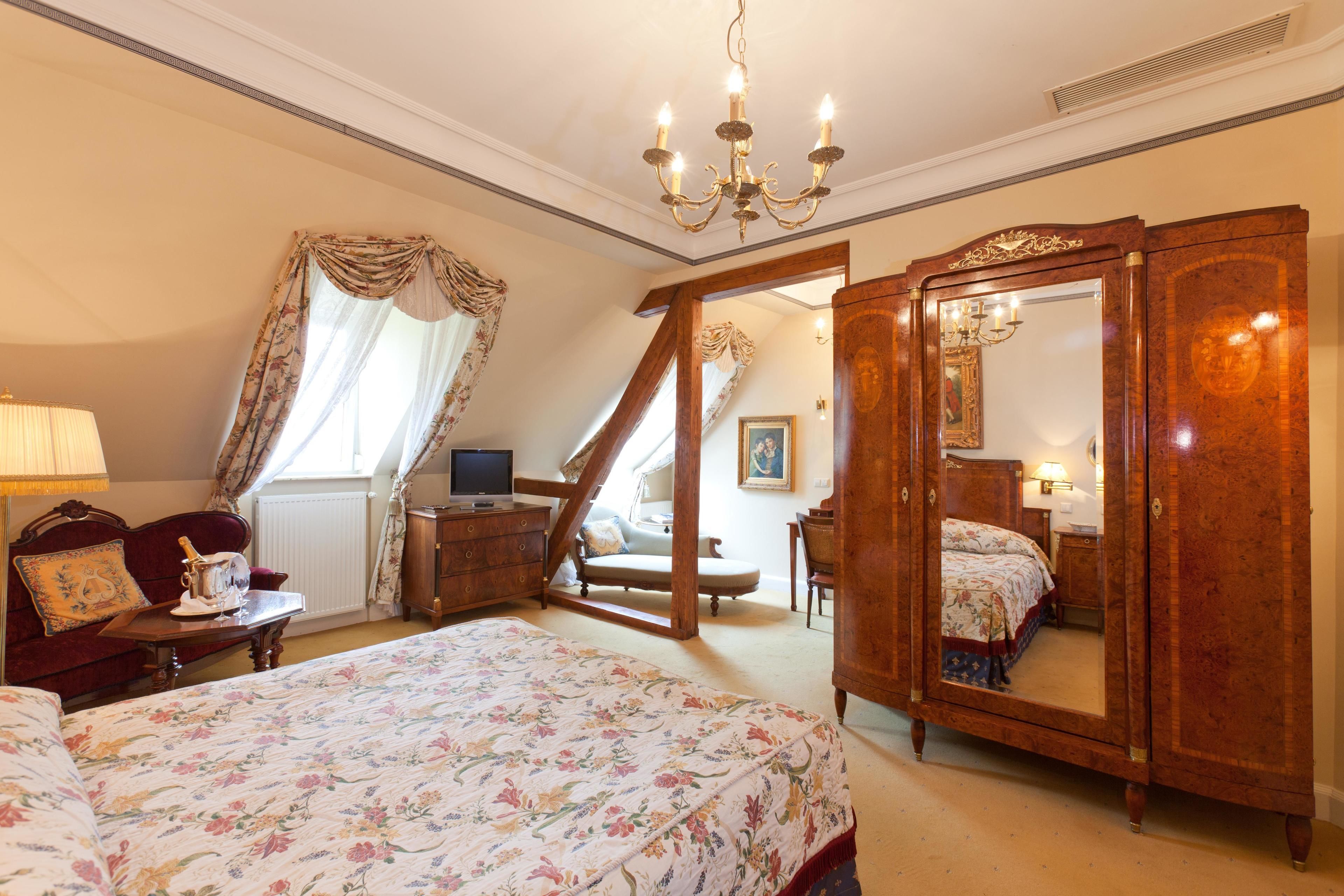 Quarto com uma cama grande, guarda-roupa de madeira, escrivaninha com computador, cadeira e janela com cortinas.