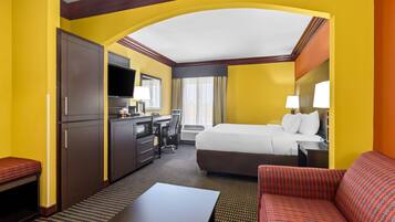 Quarto de hotel com cama, escrivaninha, cadeira e sofá.