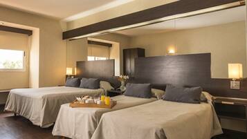 Quarto de hotel com duas camas, um espelho grande e um tabuleiro com itens de café da manhã.