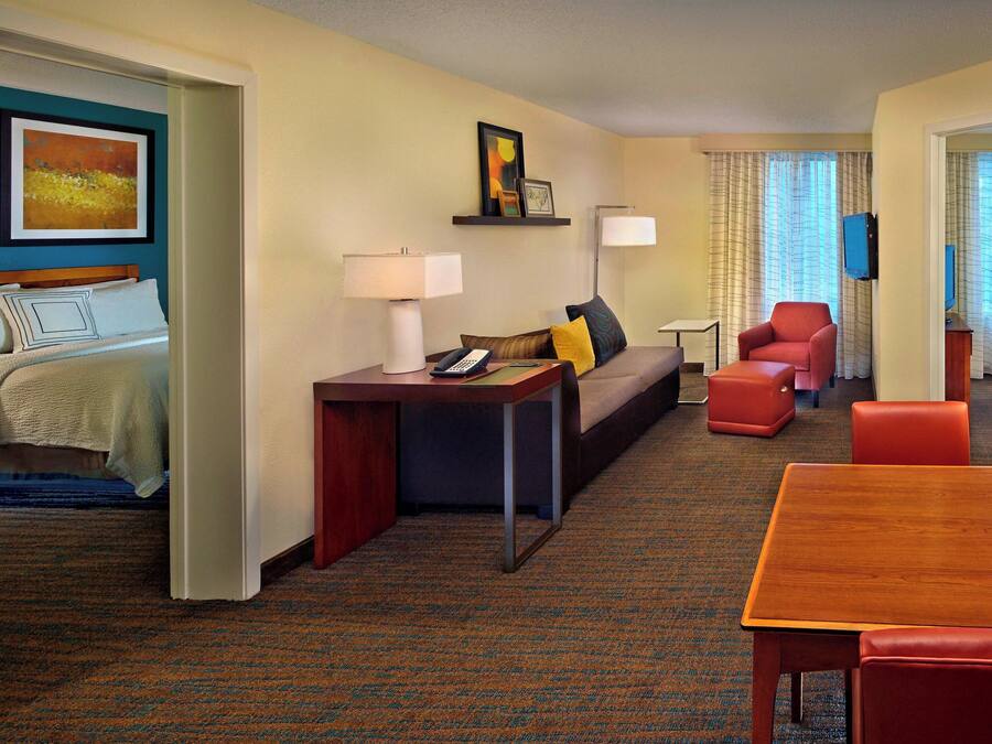 Quarto de hotel com uma cama, um sofá, uma mesa de jantar e uma televisão.